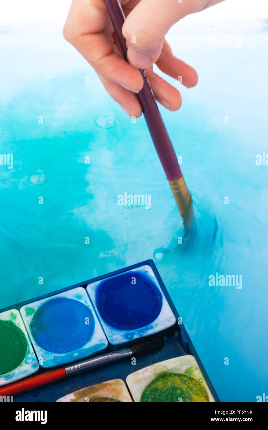 Paint dissolving in water as painting brush touching water Stock Photo ...