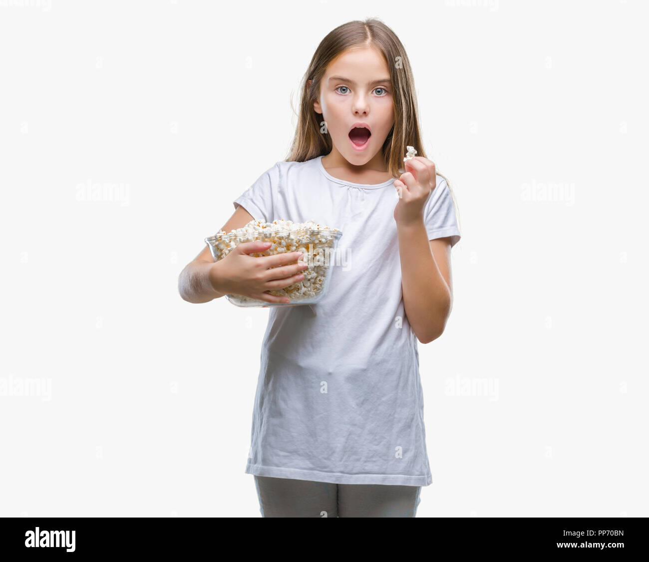 Young beautiful girl eating popcorn snack isolated background scared in ...