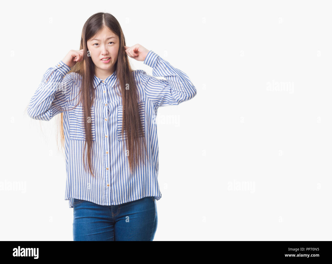 Young Chinese woman over isolated background covering ears with fingers ...