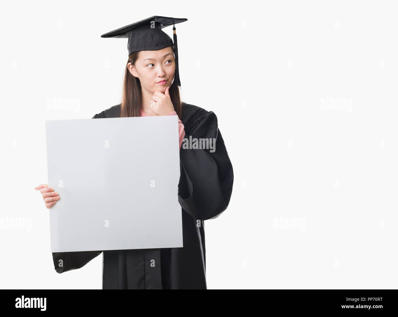 Young Chinese woman wearing graduate uniform holding banner serious ...