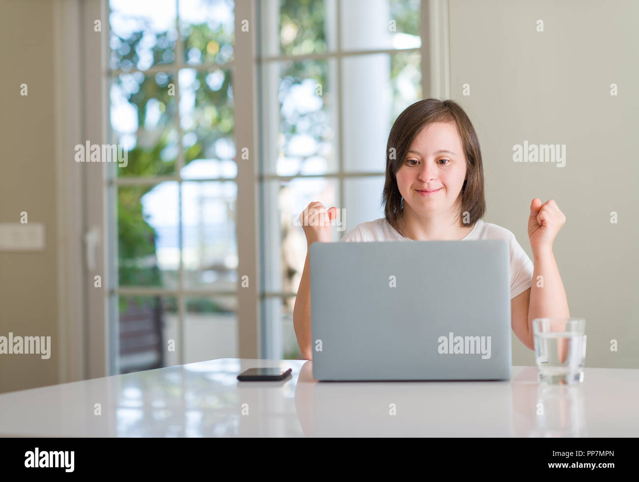 Down syndrome woman at home using computer laptop screaming proud and ...