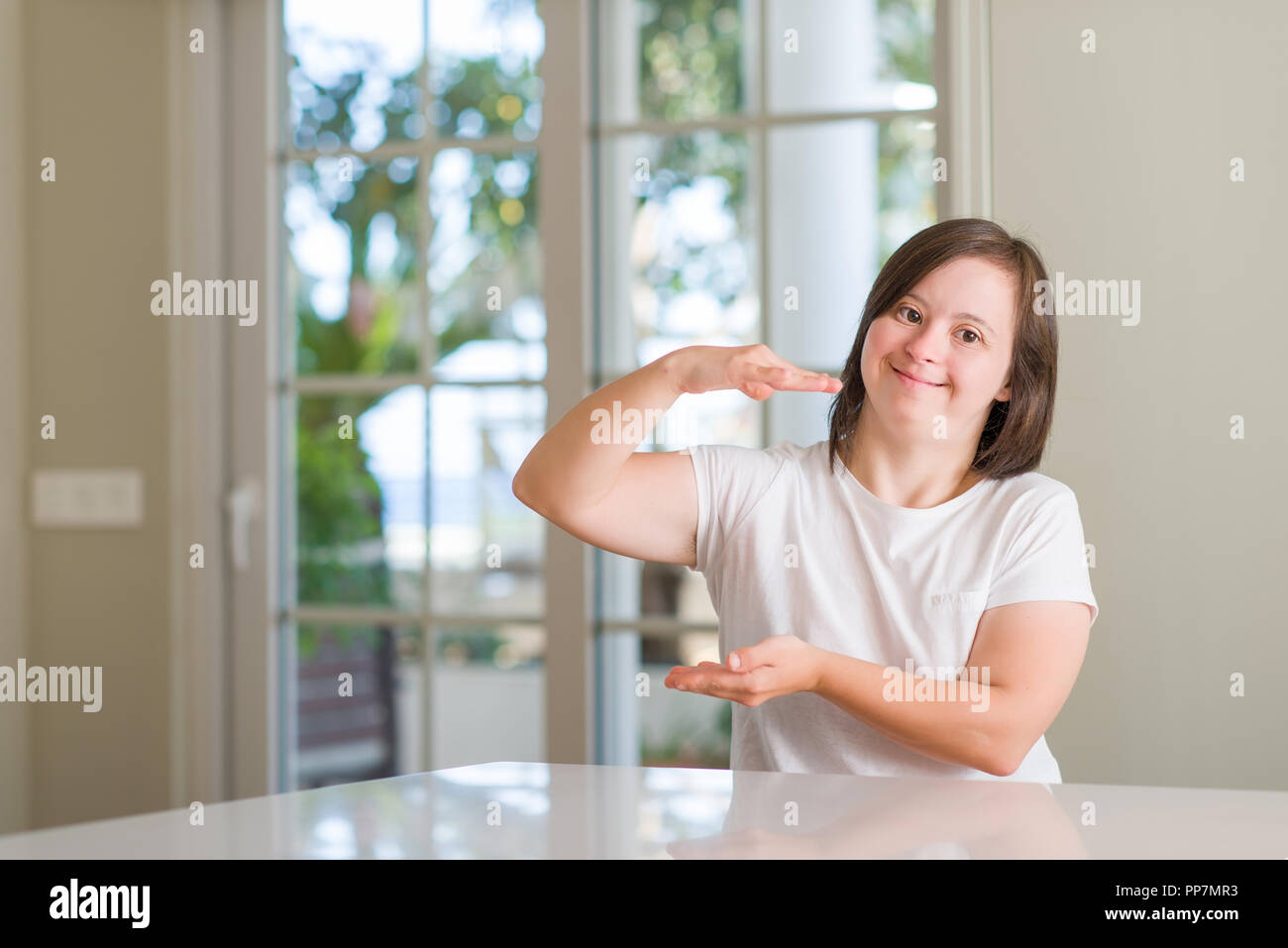 Down syndrome woman at home gesturing with hands showing big and large ...