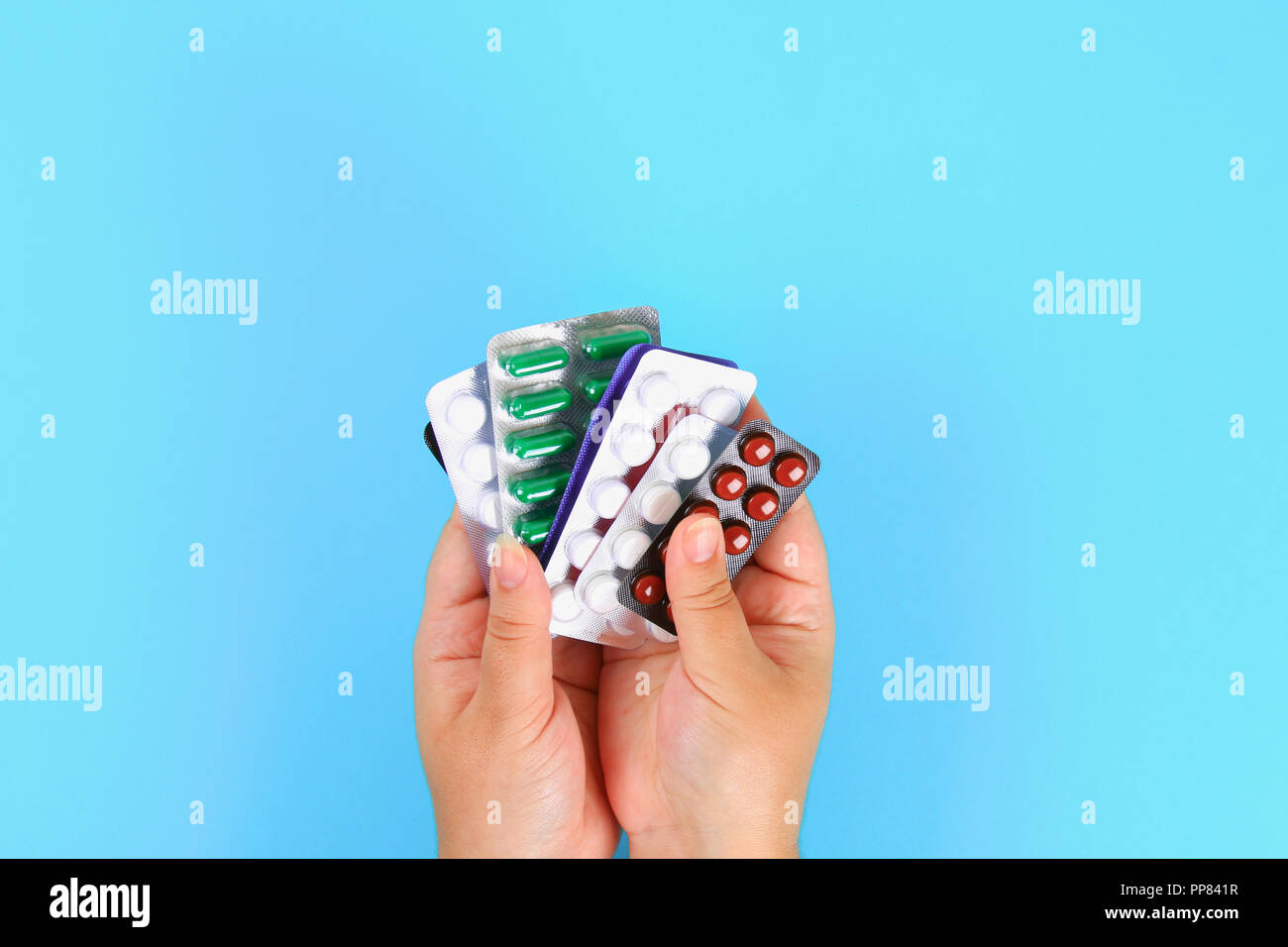 The girl holds in her hands blisters of various tablets and pills on ...