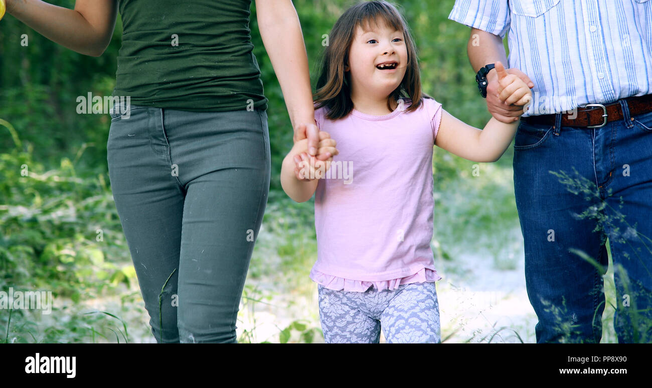 Beautiful little girl with down syndrome walking with parents Stock ...