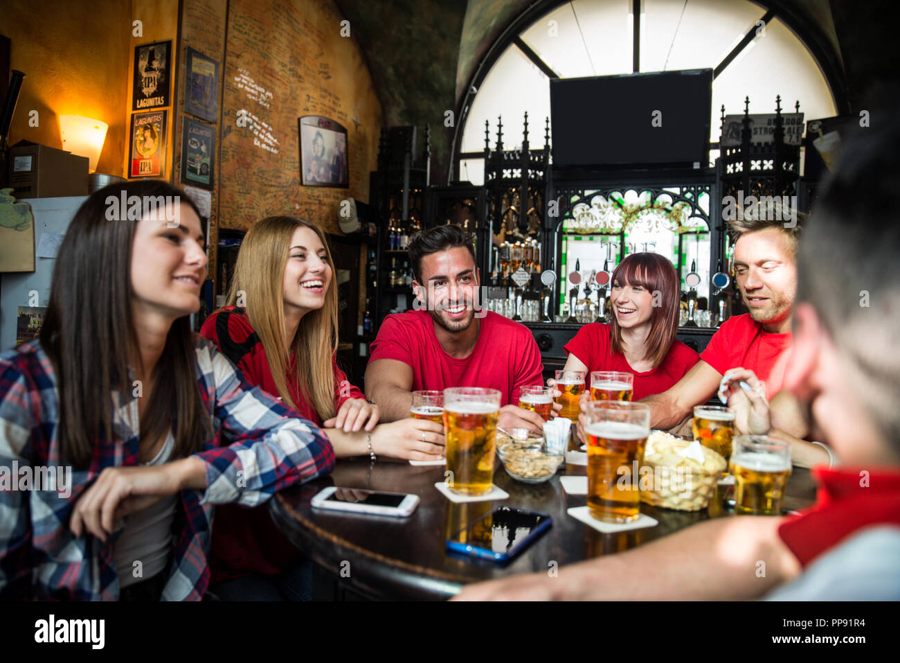 Group of friends cheering on their footbal team at pub - Group of ...