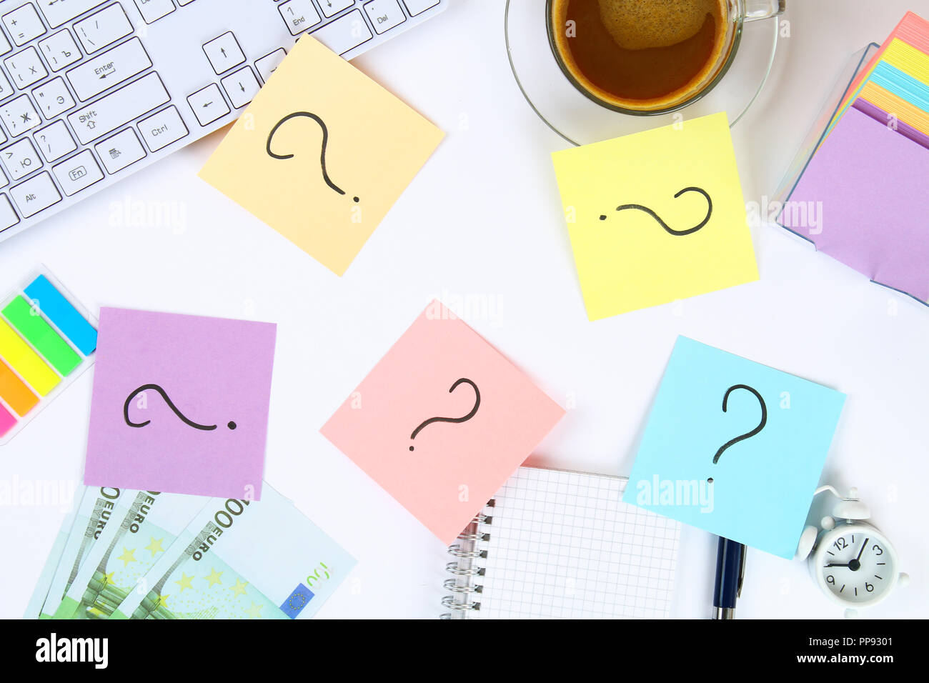 Multicolored stickers note with question mark on white desktop next to ...