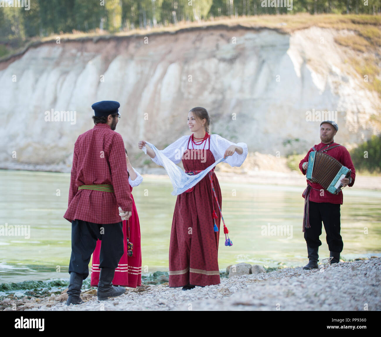 A group of young people in Russian national costumes on the background ...