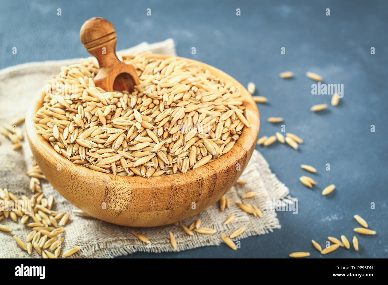 Raw grain of oats in a wooden bowl and scoop on a gray table Stock ...