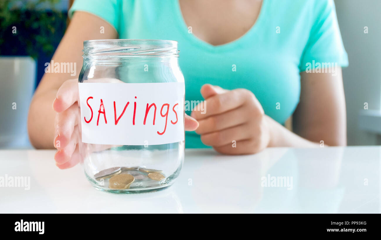 Closeup photo of young woman taking almost empty glass jar for money ...