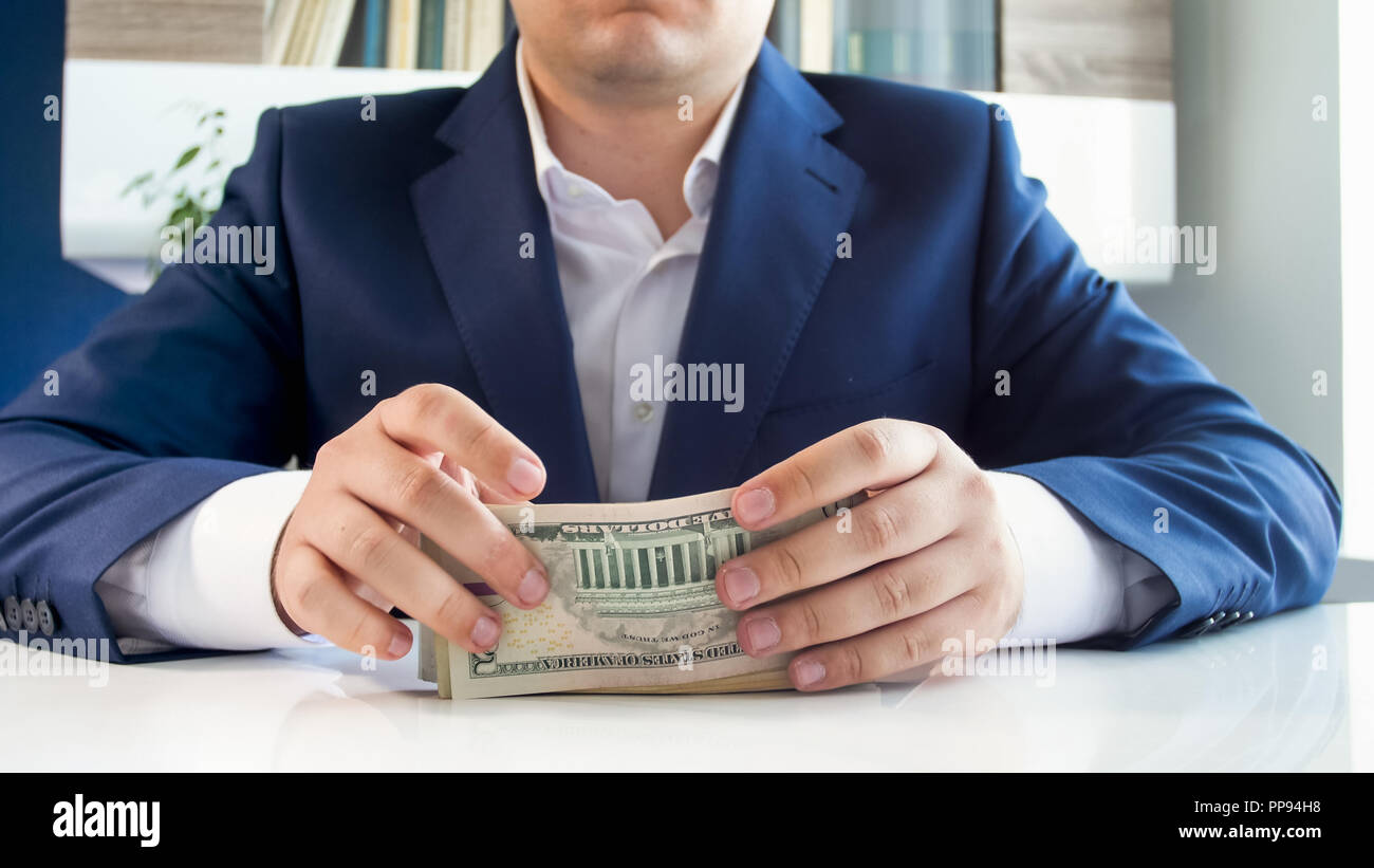 Closeup image of young successful businessman sitting behind desk and ...