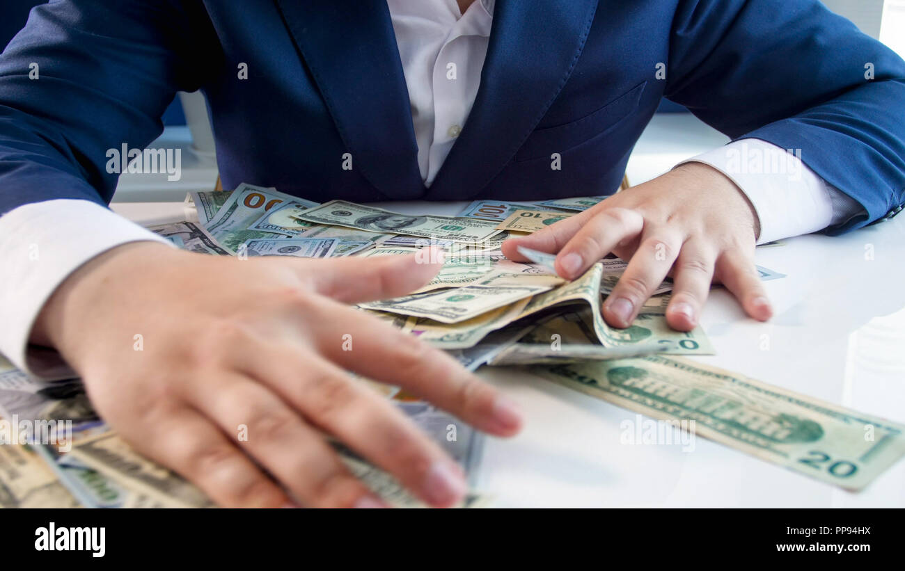 Closeup photo of greedy businessman grabbing money lying on office desk ...