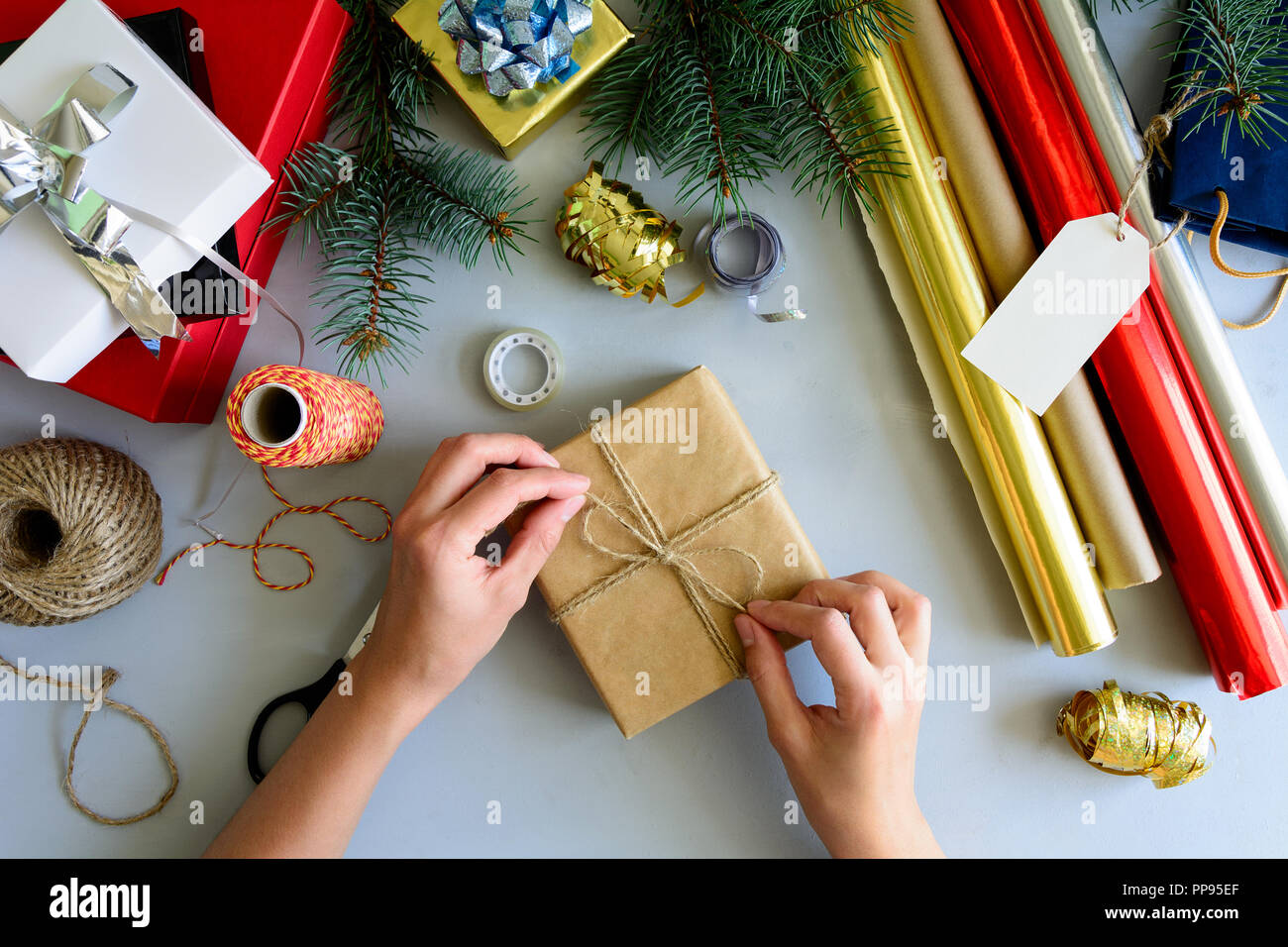 Woman's hands decorate present box on gray wooden background. New Year ...