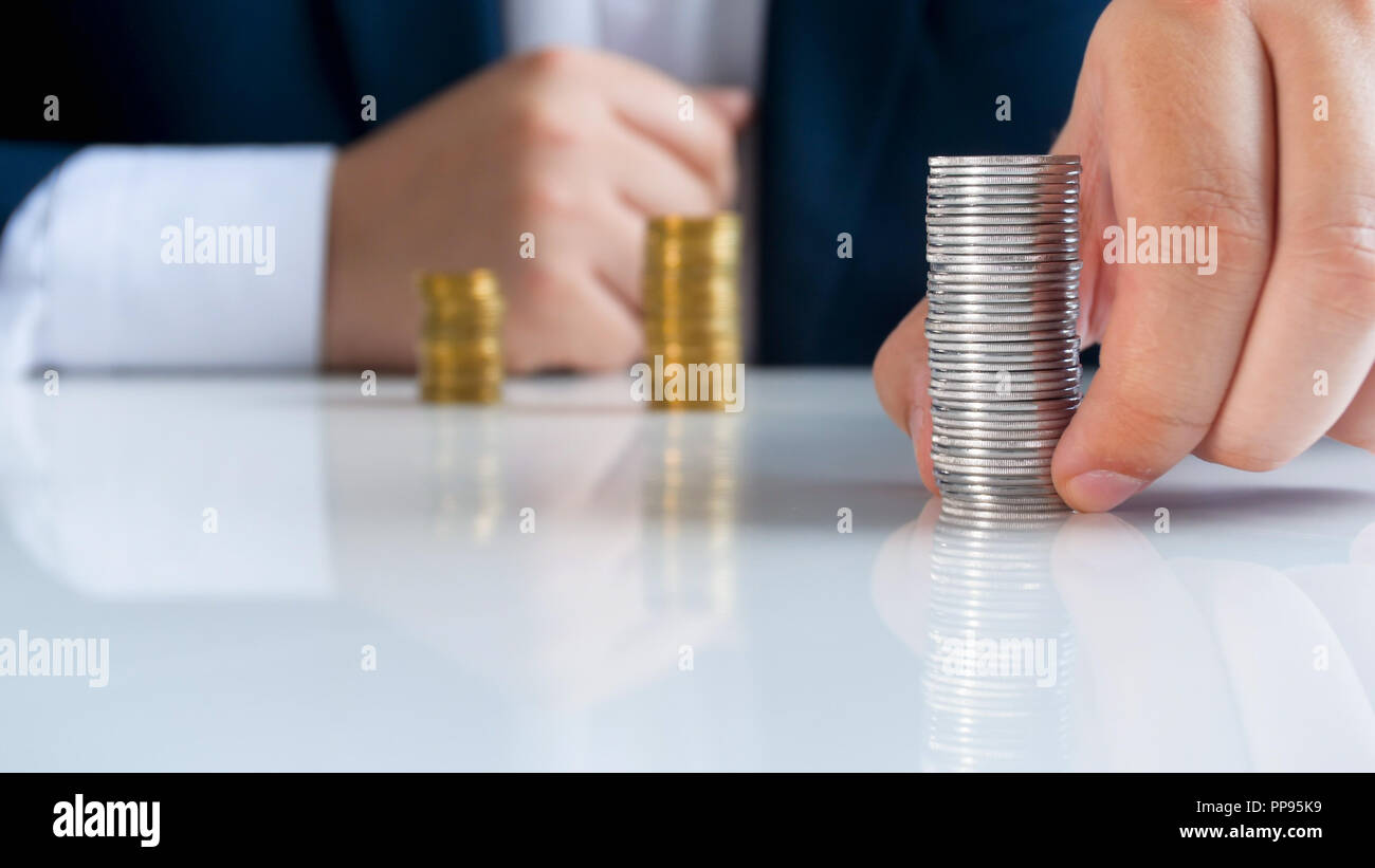 Closeup image of businessman hand moving high stack of silver coins ...