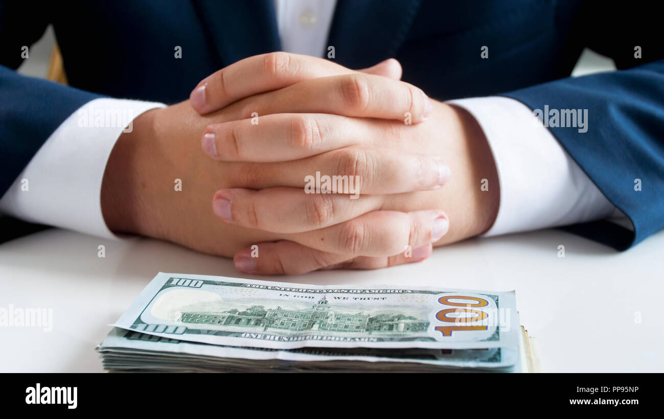 Closeup image of businessman sitting behind office desk with big stack ...