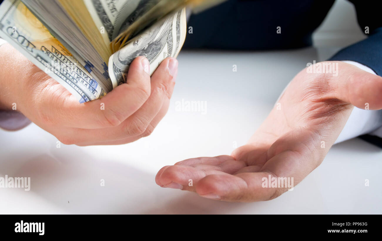 Closeup image of man in suit slapping big stack of money on hand Stock ...