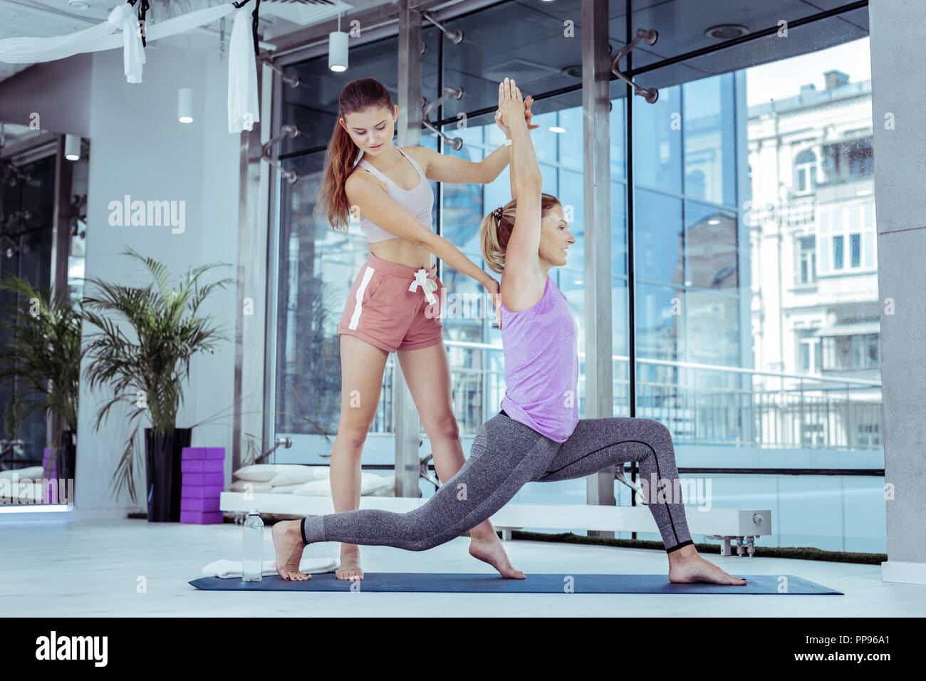 Experienced female master bettering womans yoga pose Stock Photo - Alamy
