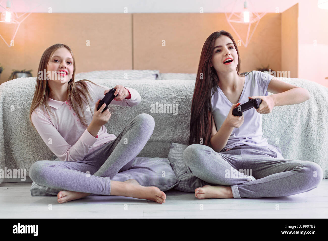 Joyful girls using consoles for playing game Stock Photo - Alamy