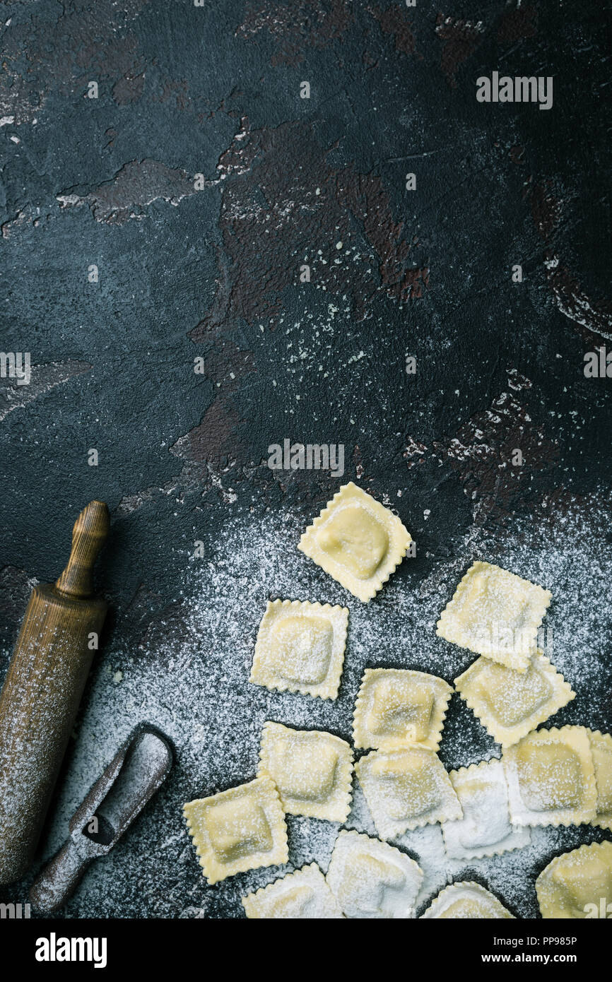 Fresh ravioli with flour on dark stone background, top view. Cooking ...
