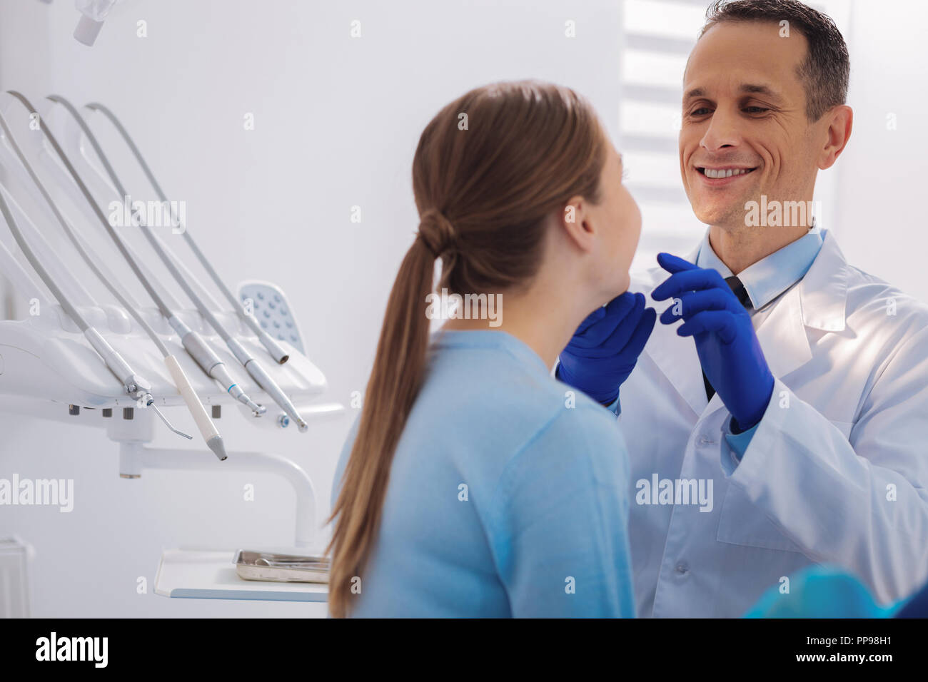 Positive dentist smiling while checking the teeth of his patient Stock ...