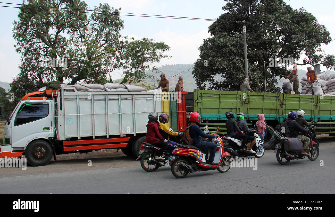 Workers move cargo from trucks to other trucks in Bandung, INdonesia ...