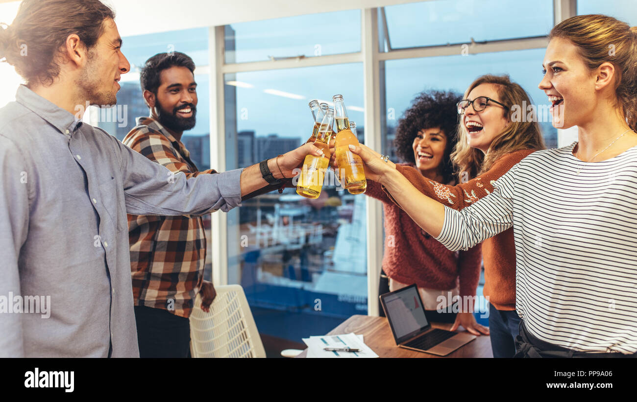 Business colleagues toasting beer to celebrate success in office ...