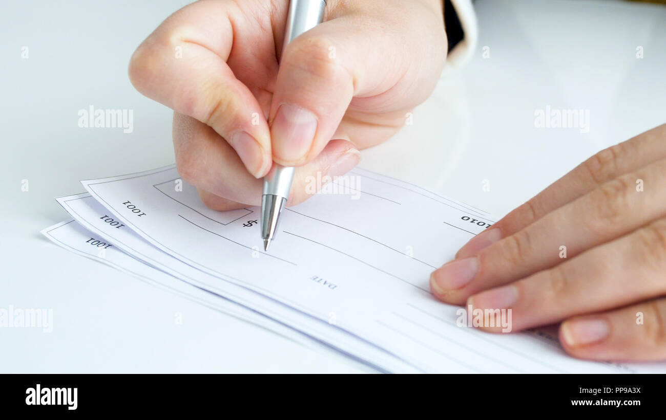 Closeup image of female hand signing banking cheque Stock Photo - Alamy
