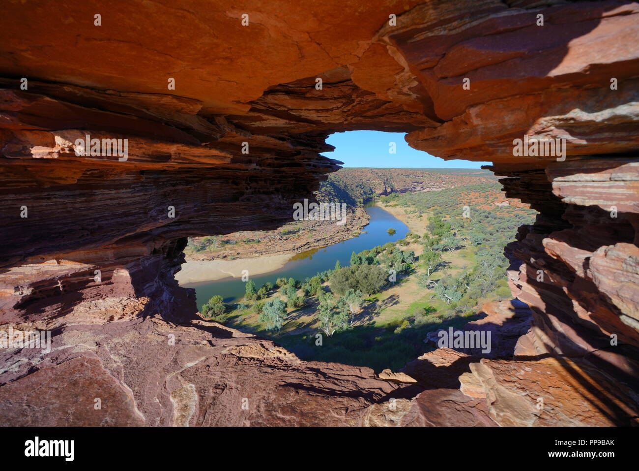 a view from the middle of hollow rock formation facing a river in the ...