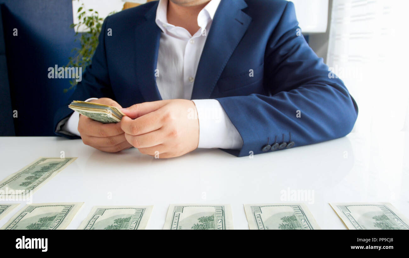 Closeup image of businessman sitting behind desk and laying stack of ...