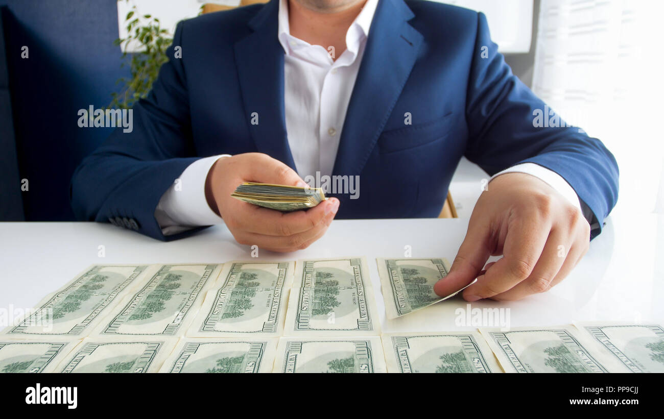 Closeup photo of businessman sitting behind desk and laying money in ...