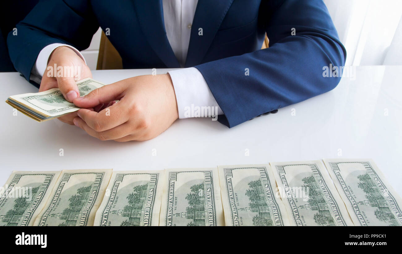 Closeup photo of businessman in suit holding stack of money and laying ...