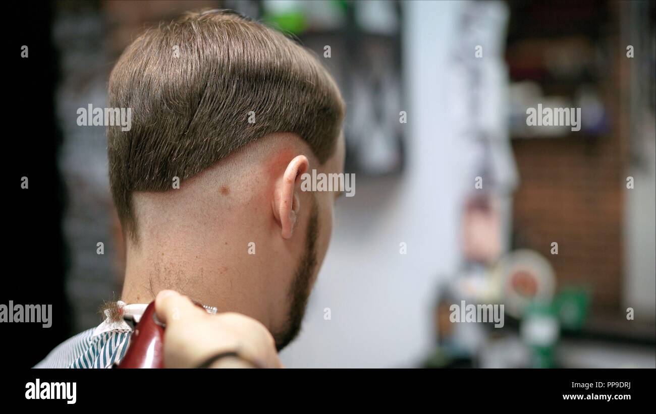 Men's haircut in barbershop. Master barber does a haircut to the client ...