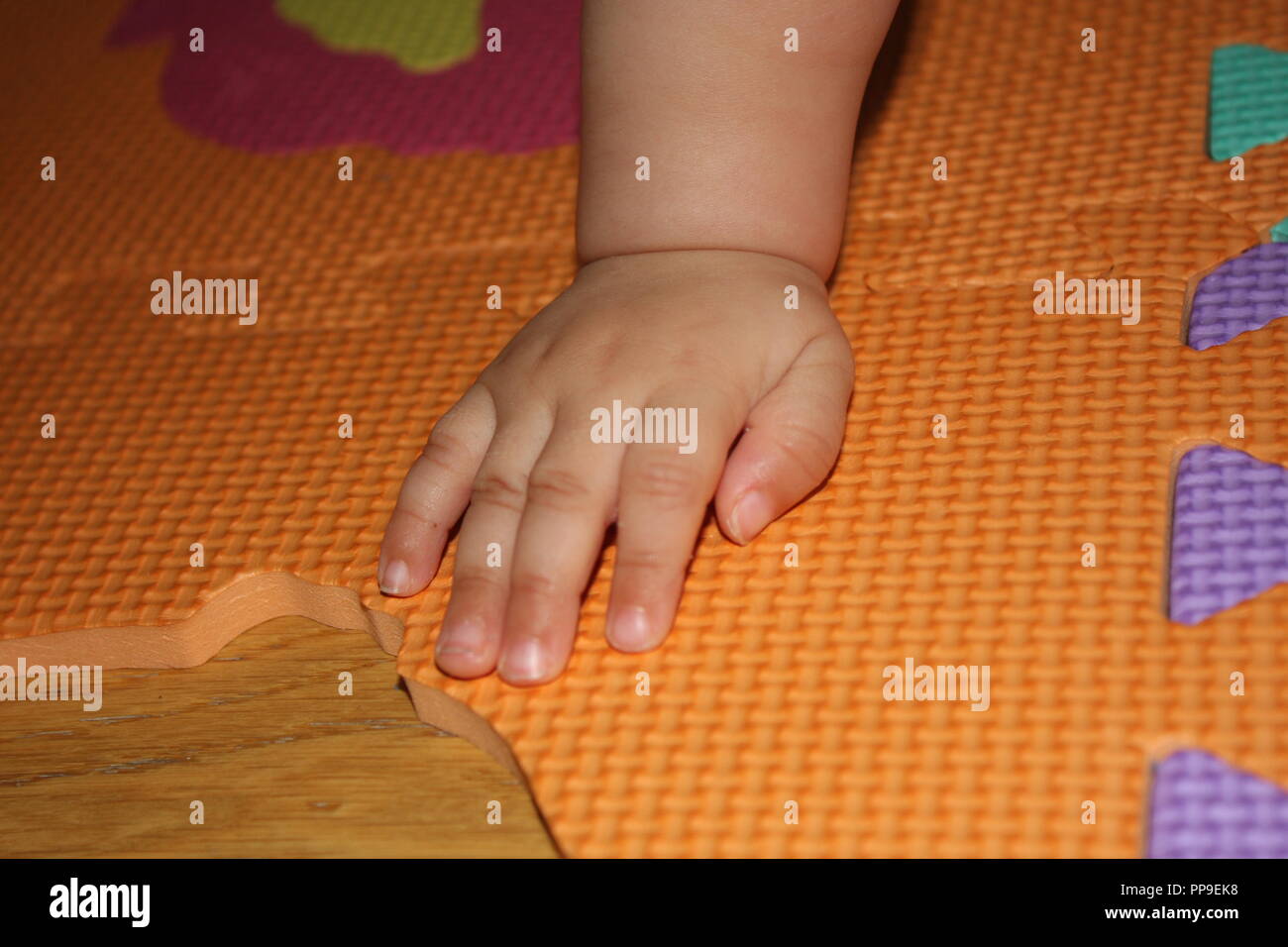 little baby hand plays on toy carpet Stock Photo - Alamy