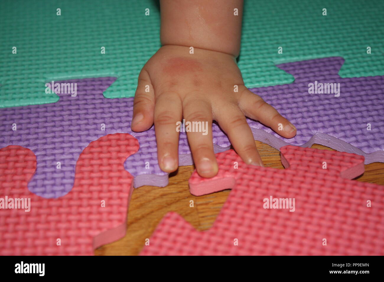 little baby hand plays on toy carpet Stock Photo - Alamy