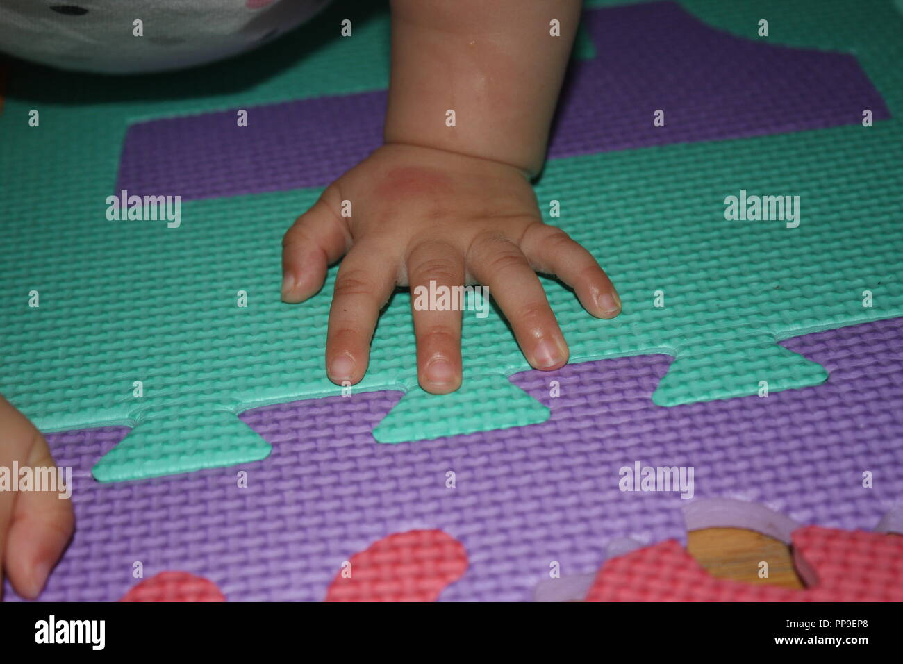 little baby hand plays on toy carpet Stock Photo - Alamy