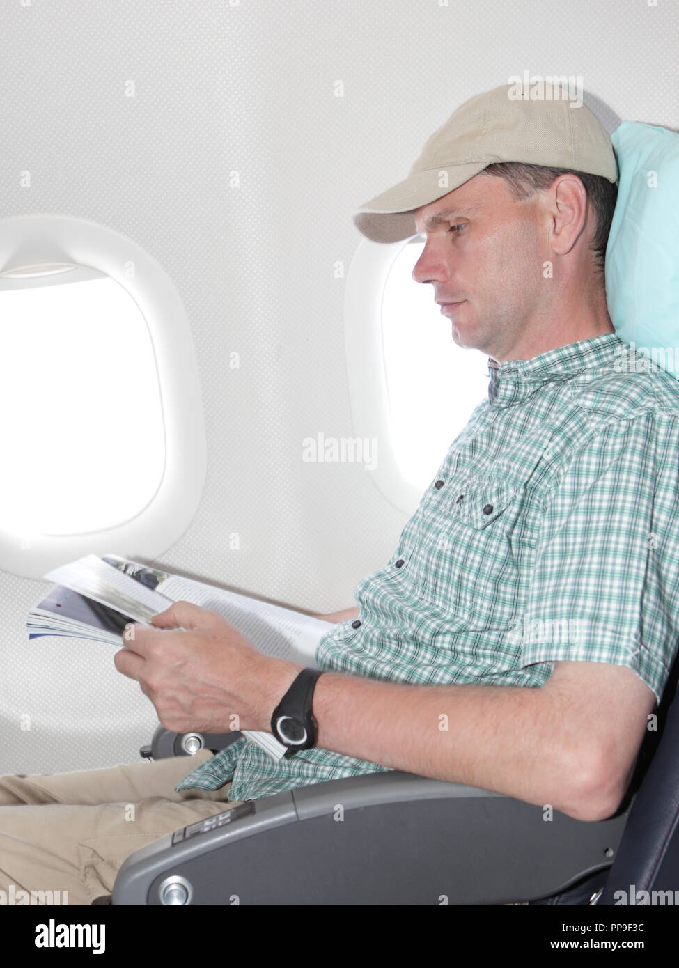 Passenger reading a magazine in airplane Stock Photo - Alamy