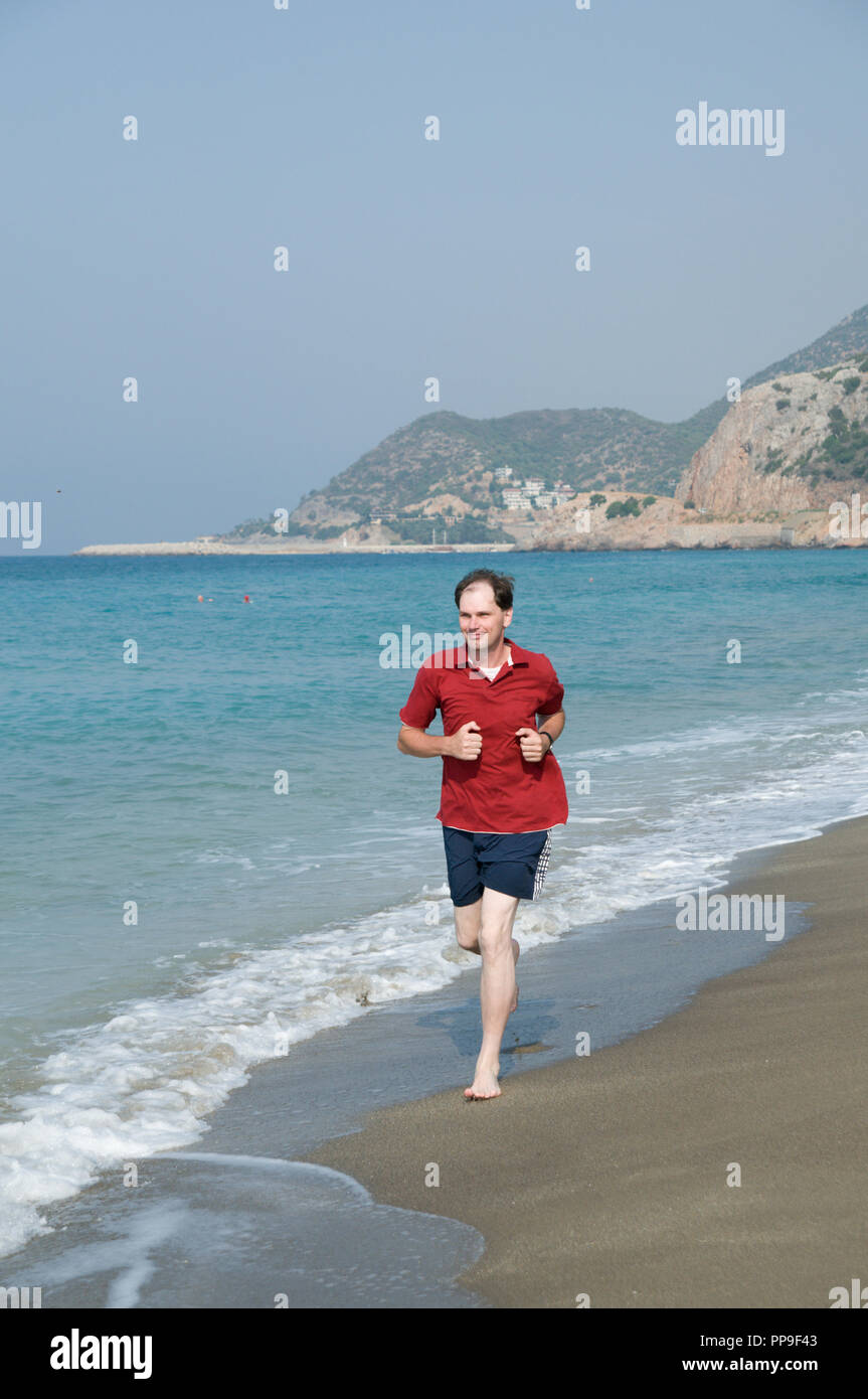 Barefoot man jogging on the beach Stock Photo - Alamy