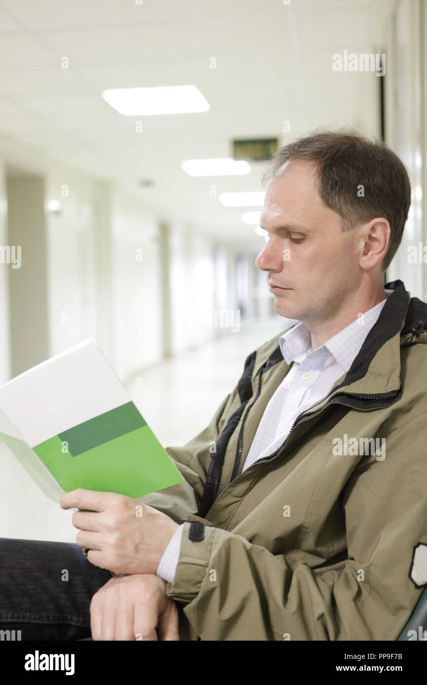 Patient reading health booklet in waiting room of hospital Stock Photo ...