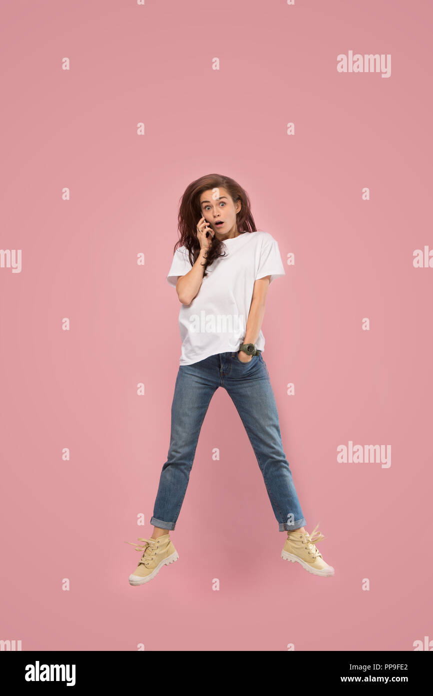 Always on mobile. Full length of pretty young surprised woman taking ...