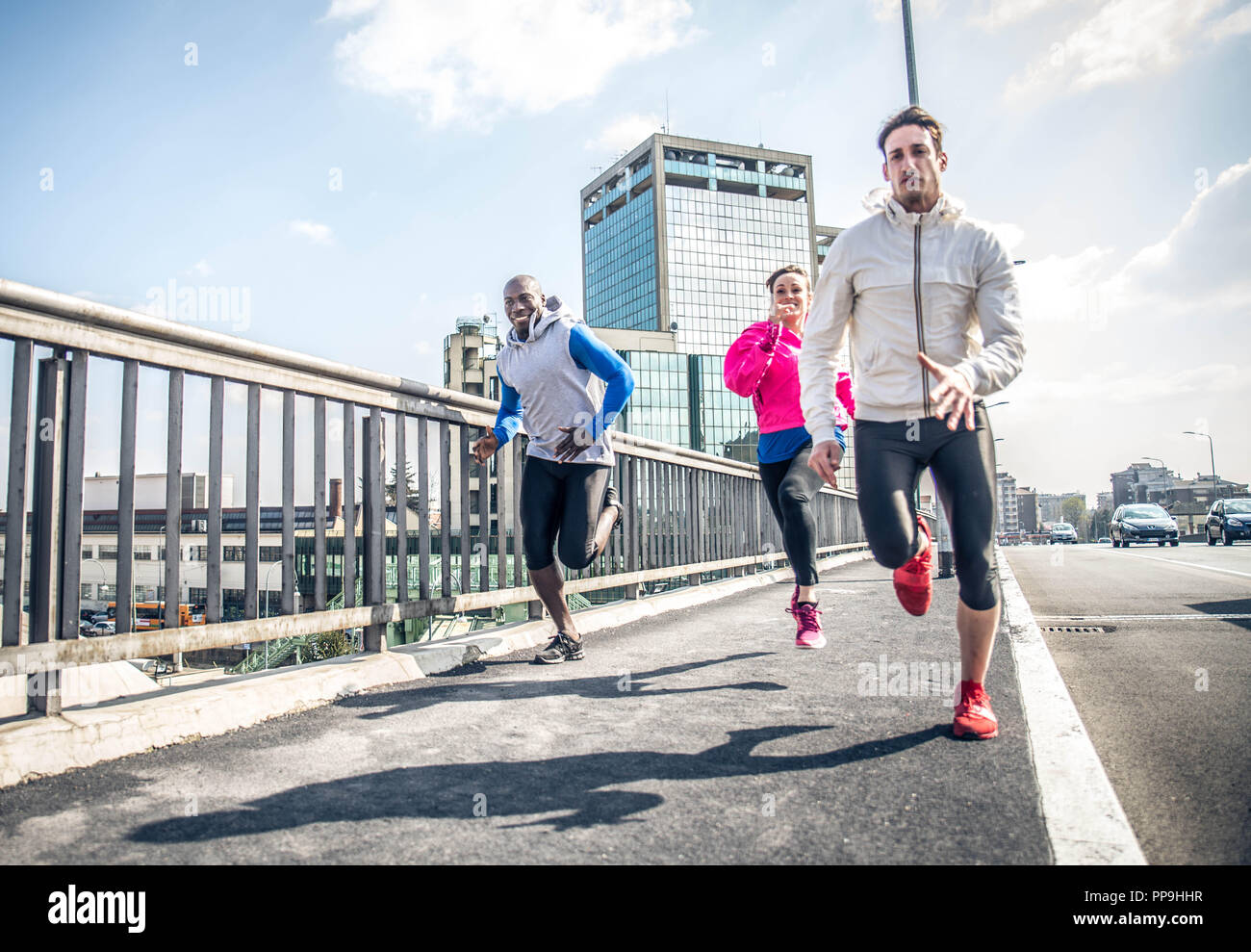 Three runners sprinting outdoors - Sportive people training in a urban ...