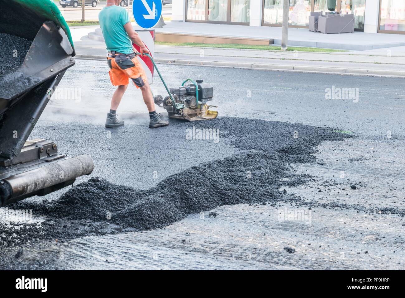 Road workers compact the asphalt with a vibrating rammer on the road ...