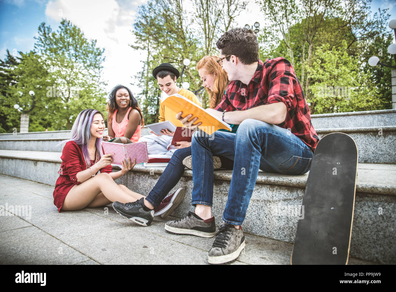 Multi-ethnic group of students stdying together outdoors in a college ...