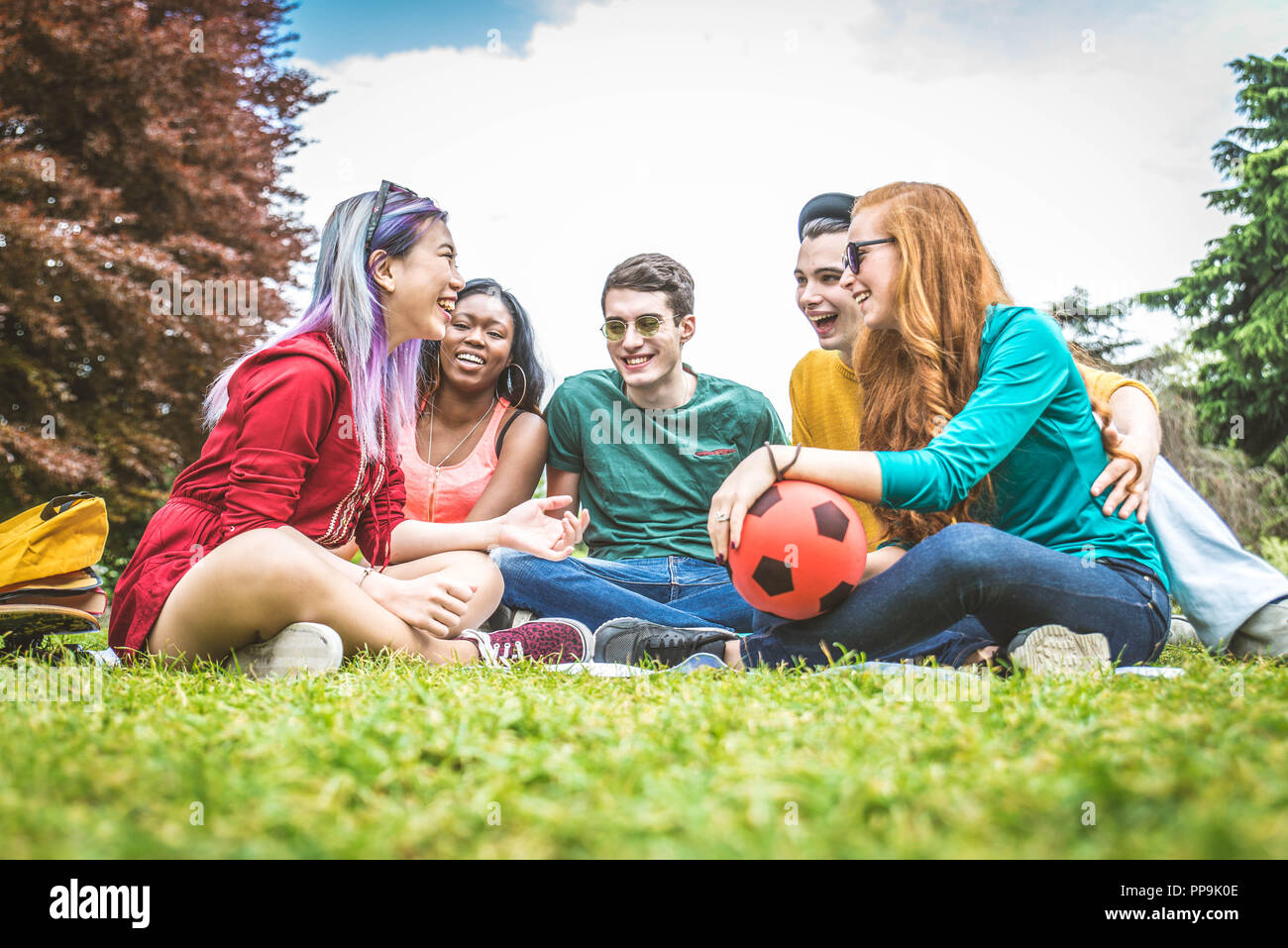 Group of multicultural people having fun while bonding in a park ...