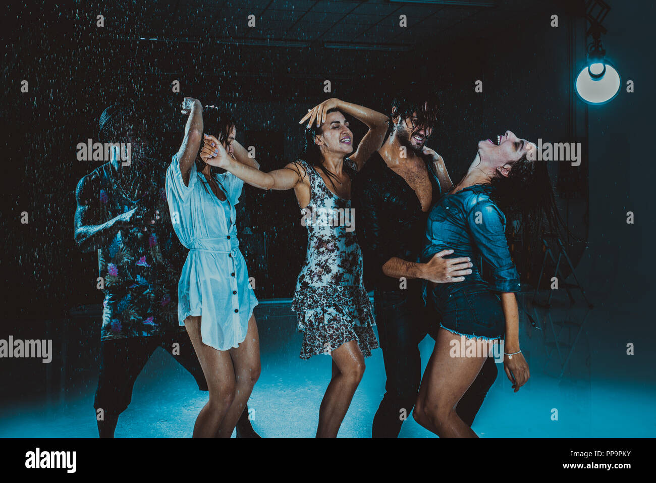 Group of friends dancing under the rain - Multiethnic people having ...