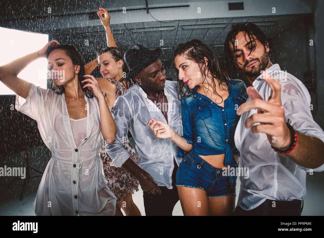 Group of friends dancing under the rain - Multiethnic people having ...
