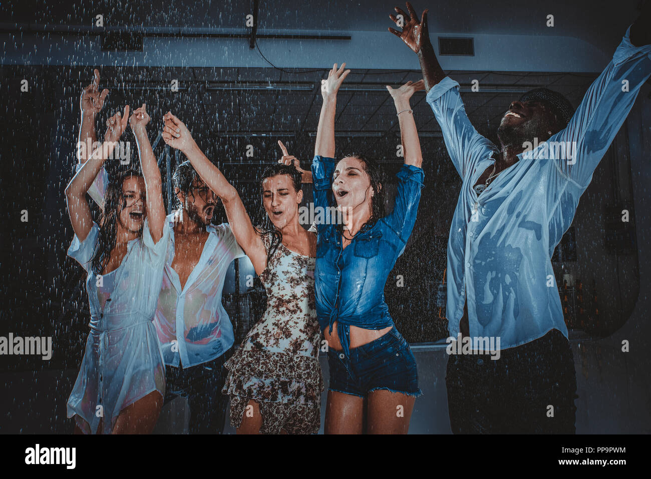 Group of friends dancing under the rain - Multiethnic people having ...