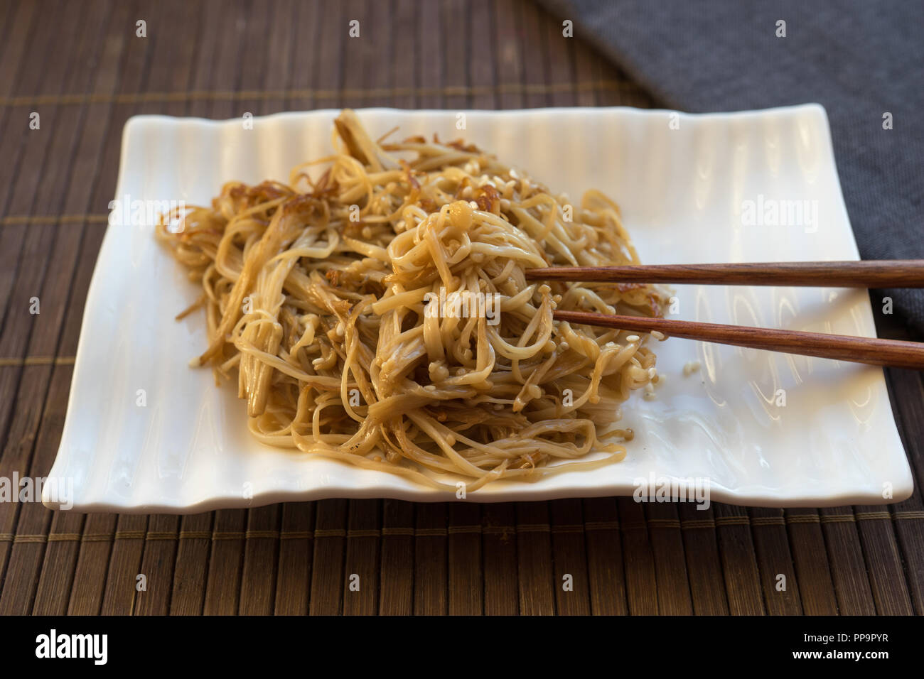 fried enoke mushrooms in soy sauce on a white plate. Asian food Stock ...