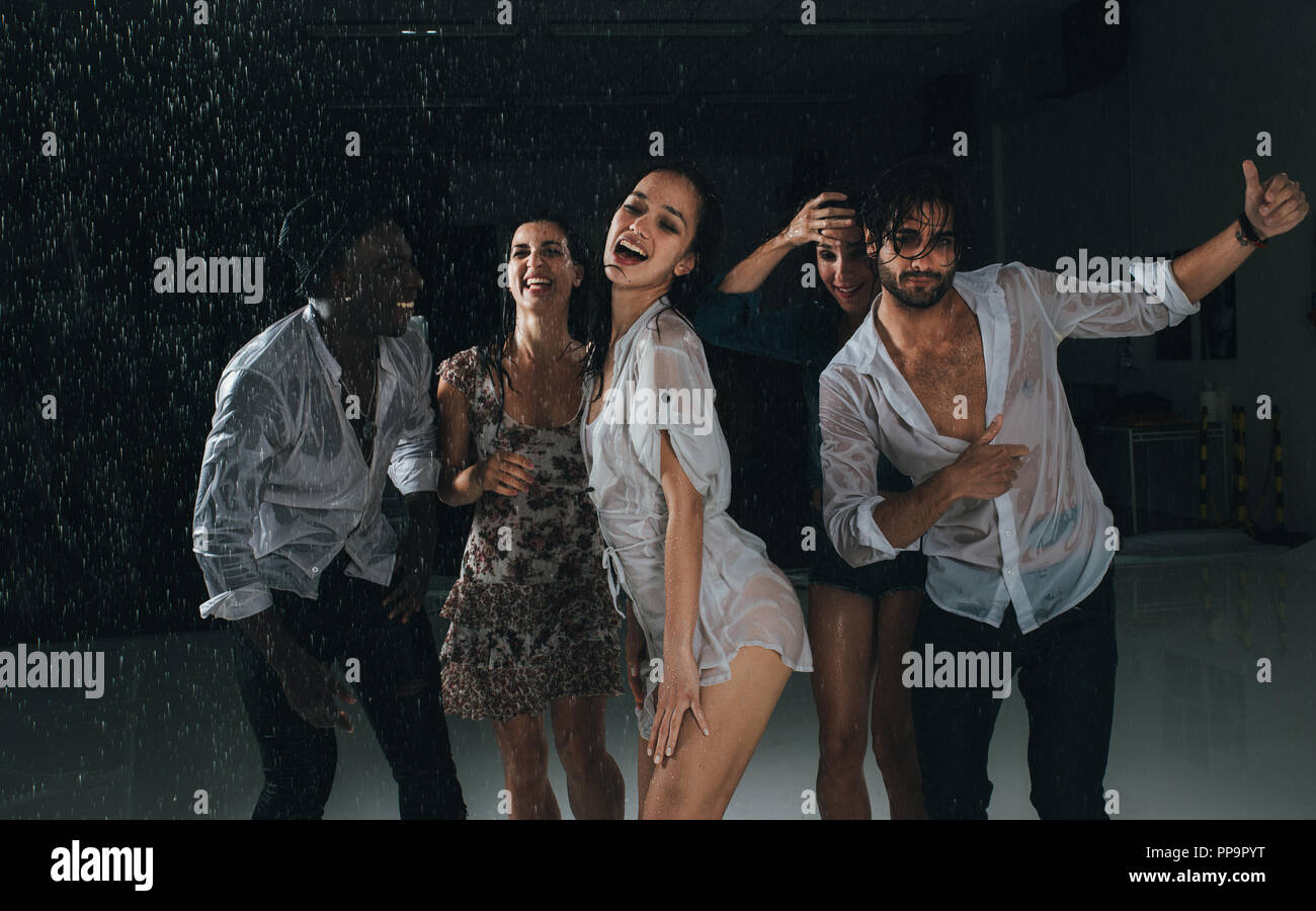 Group of friends dancing under the rain - Multiethnic people having ...