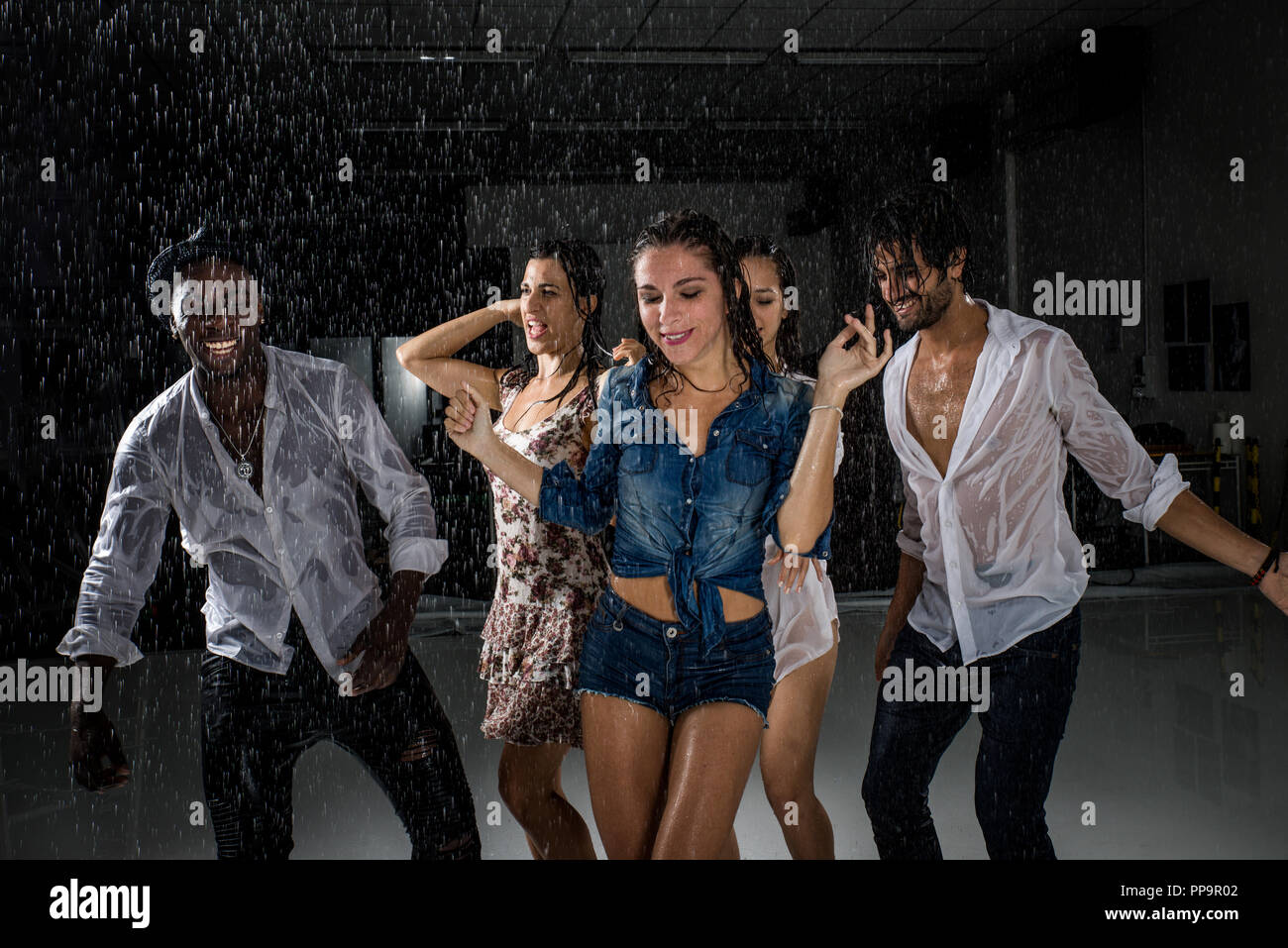 Group of friends dancing under the rain - Multiethnic people having ...