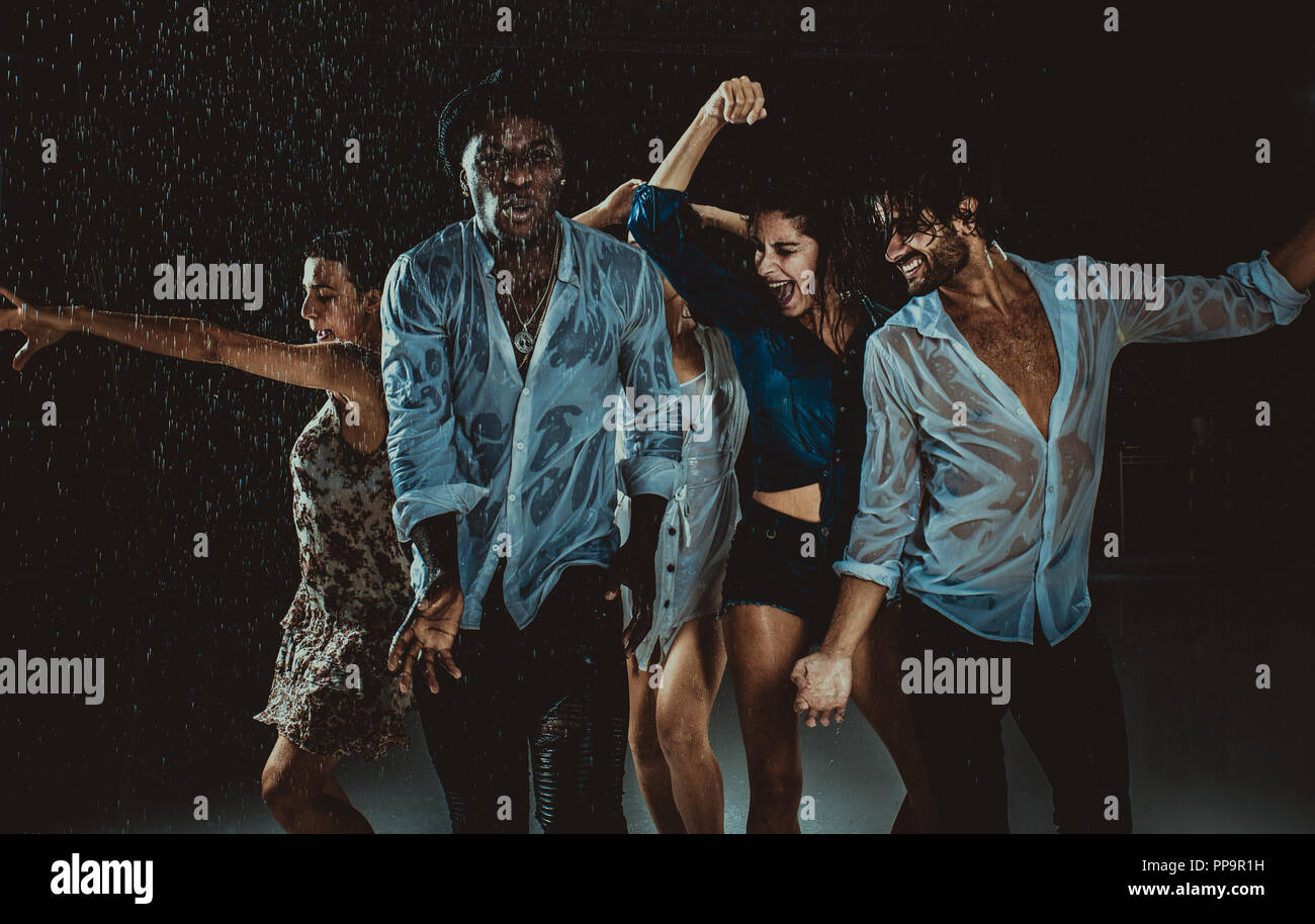 Group of friends dancing under the rain - Multiethnic people having ...