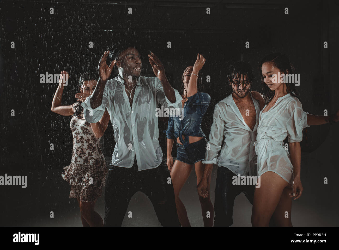 Group of friends dancing under the rain - Multiethnic people having ...